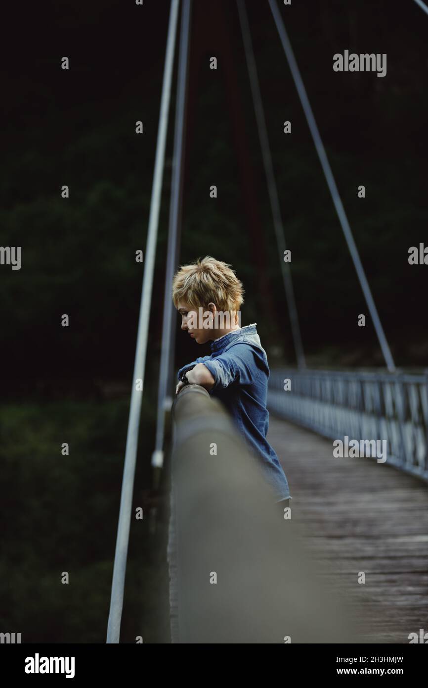 young woman looks down leaning over the edge of the bridge, in the ...
