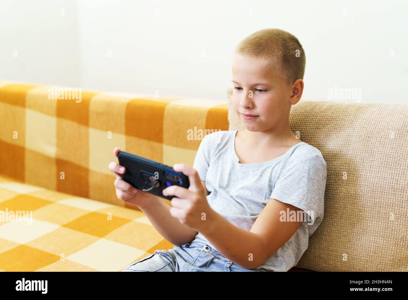 Close-up of cute little boy using smartphone looking at screen, curious ...