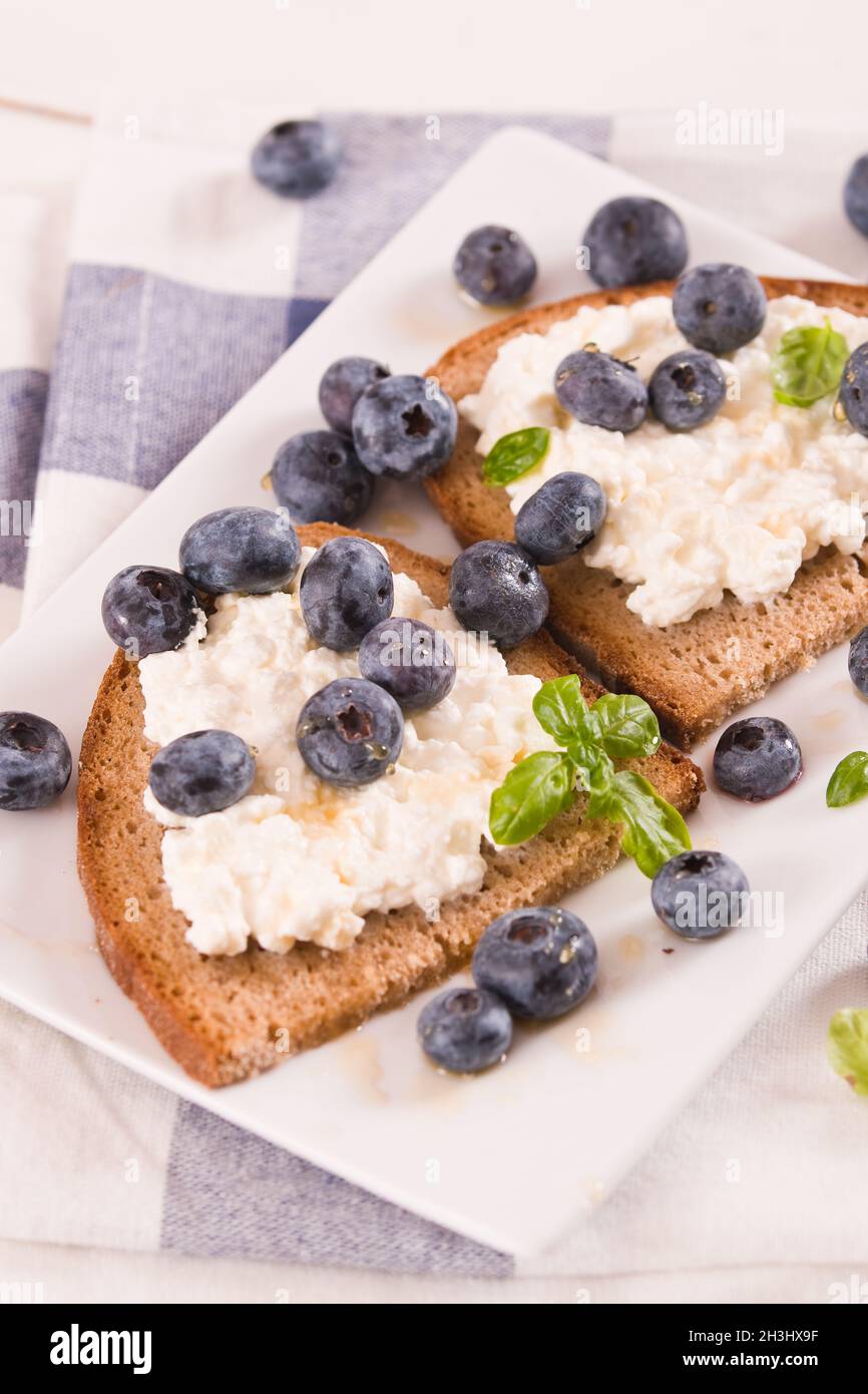 Rye bread with cottage cheese, blueberries and honey Stock Photo - Alamy