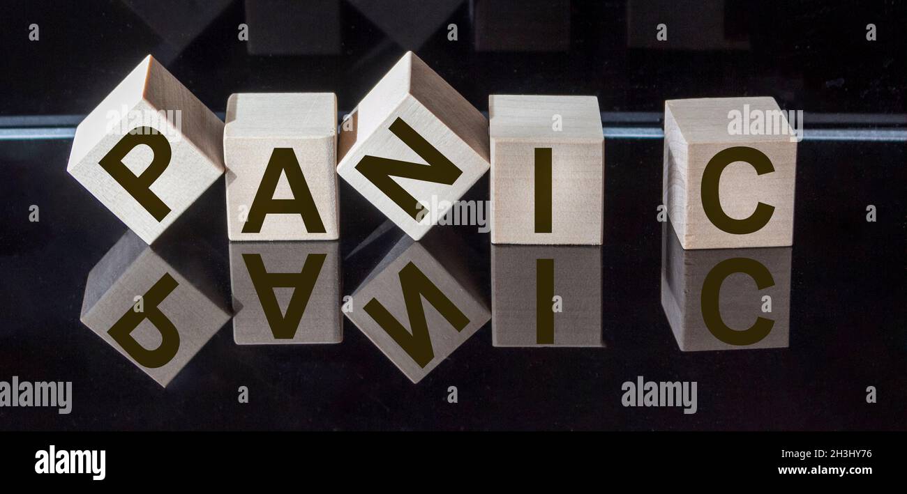 PANIC word made from wooden square letters on black glossy background ...