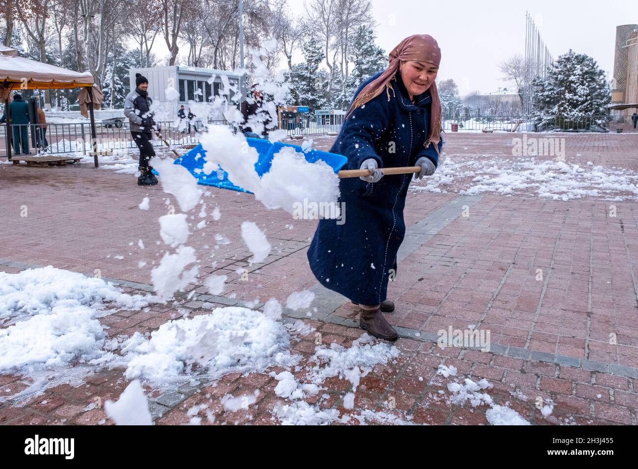 A woman clears the snow from registan square, Samarkand, Uzbekistan ...