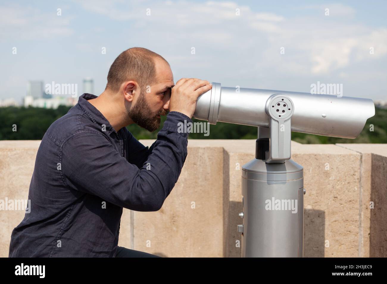 Man tourist standing on building rooftop looking through binocular ...