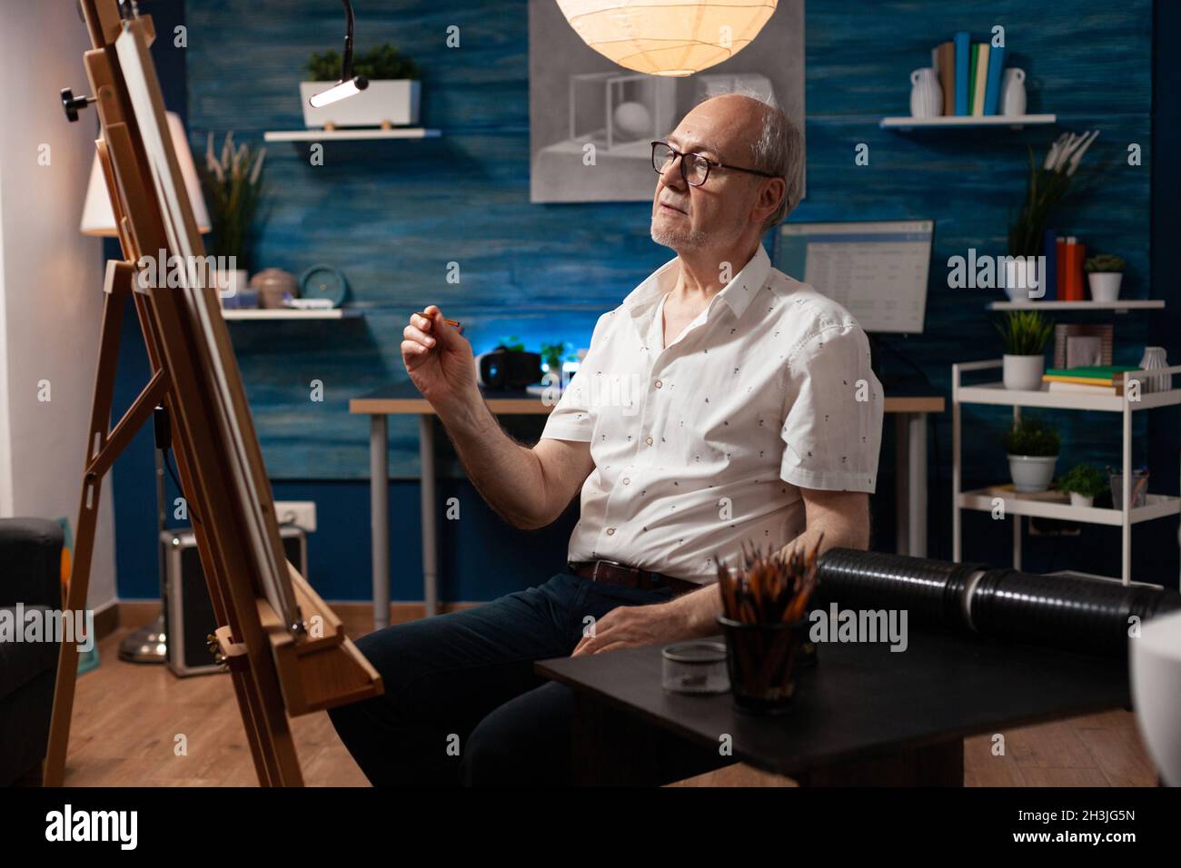 Elder artist with creativity holding pencil to draw on canvas with ...