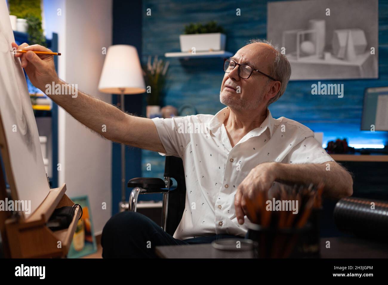 Portrait of elder man with handicap drawing on canvas using pencil for ...