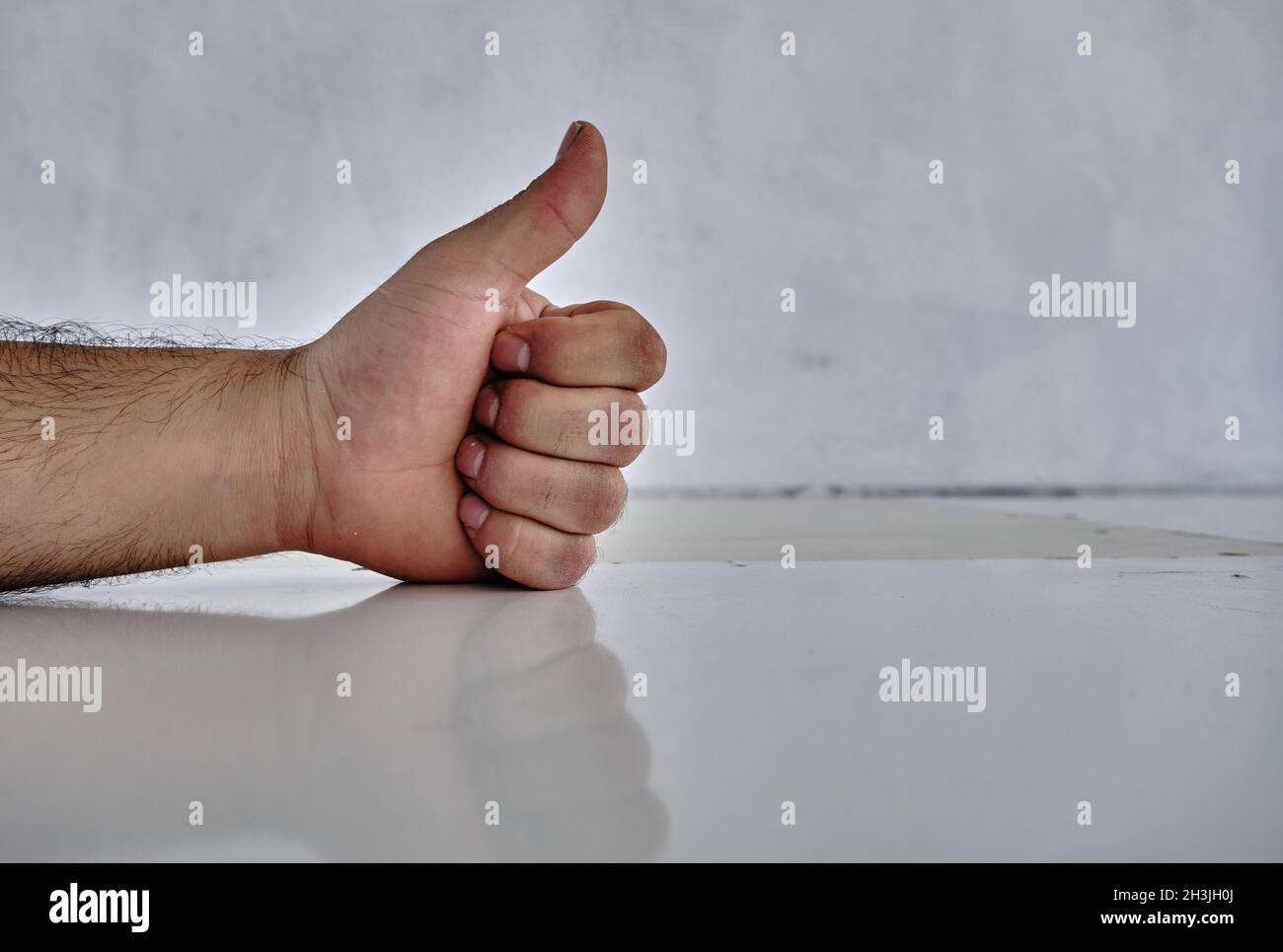 OK or OKEY sign made by man hand and its reflection on white surface of ...