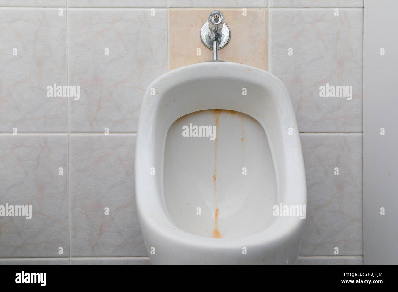 urinal with traces of limescale and rust, tile toilet before cleaning ...