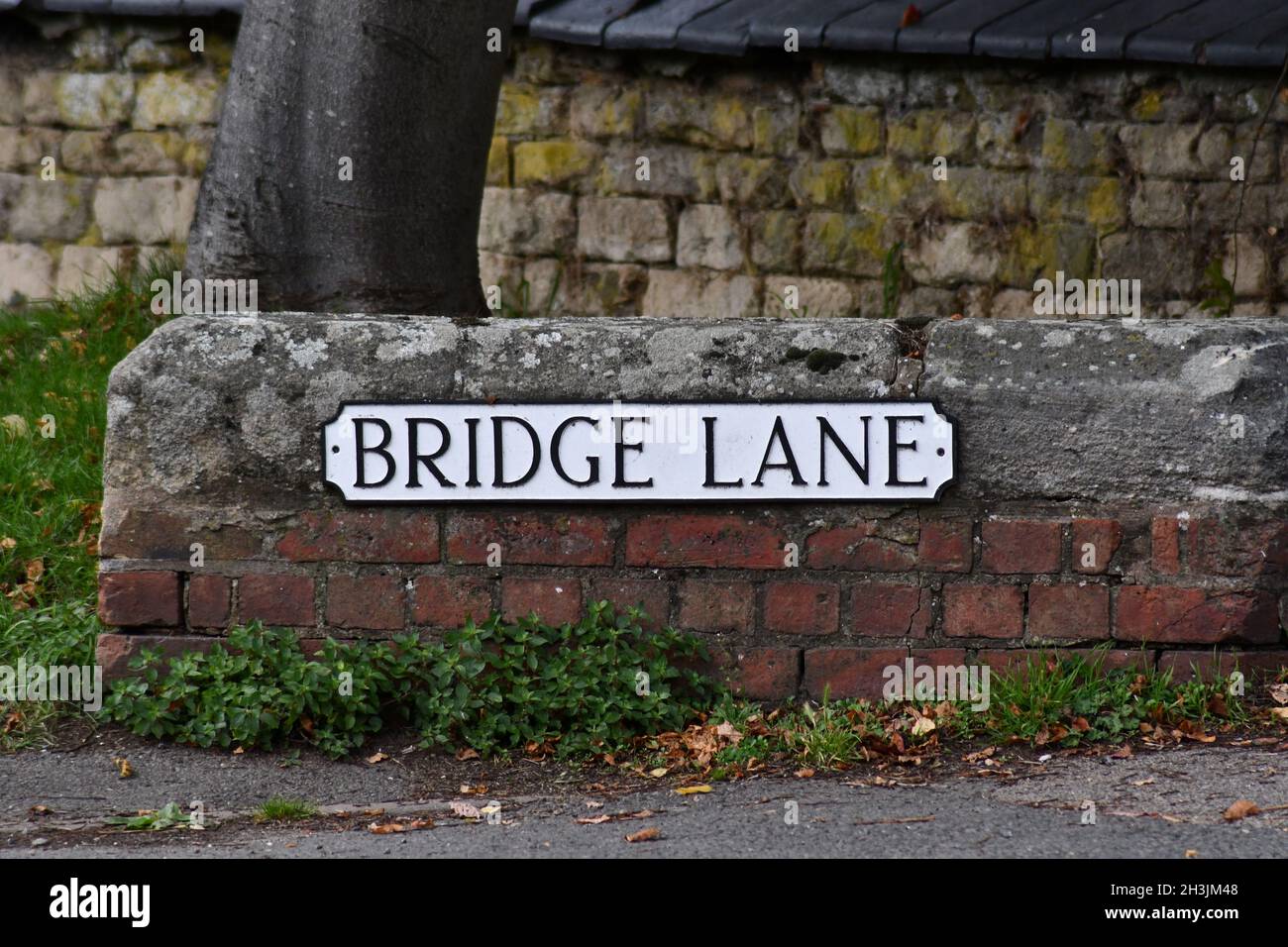A street sign on an English rural small brick wall topped with Concrete ...