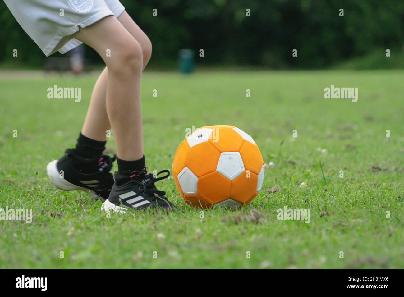 Legs of young caucasian boy playing football on grass Stock Photo - Alamy