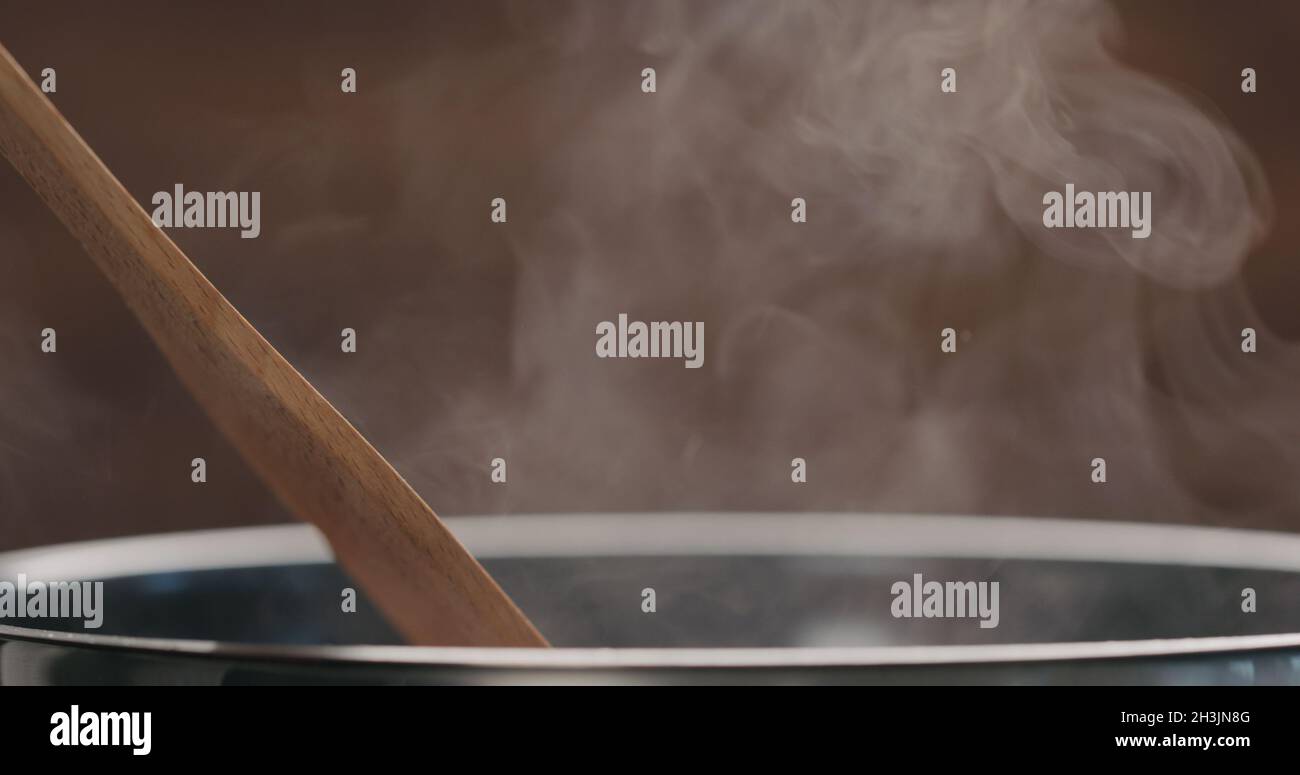 moving something in steel frying pan with wooden spatula, wide photo ...