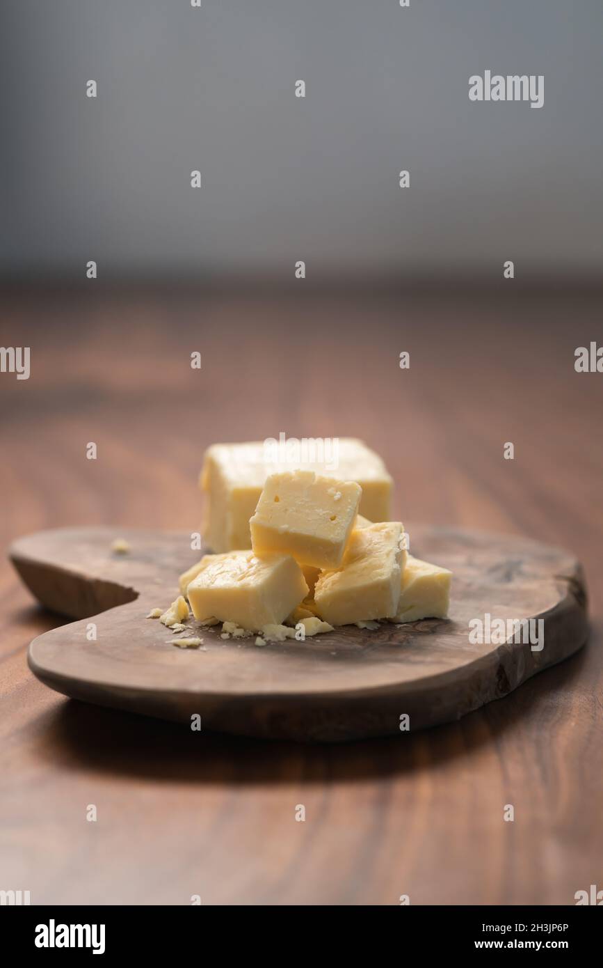 White cheddar cheese pieces on olive wood board, shallow focus Stock ...