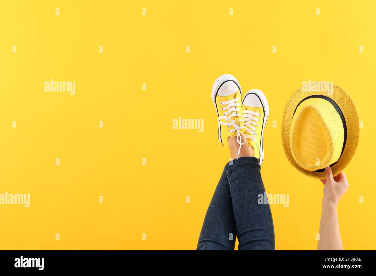 Female legs in jeans and sneakers, and female hand holding hat on ...