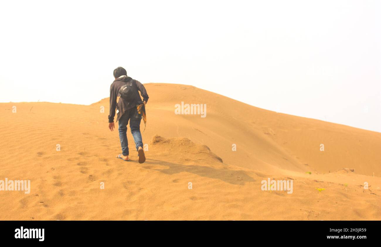 A man walking on a sand dune in a desert Stock Photo - Alamy
