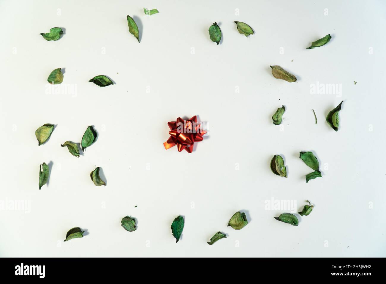 Small red ribbon with dried green leaves on white background, top view ...