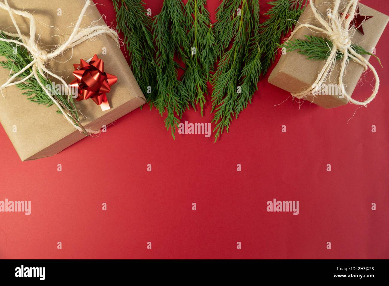 Two noel gift boxes and pine tree leafs on red background top view ...