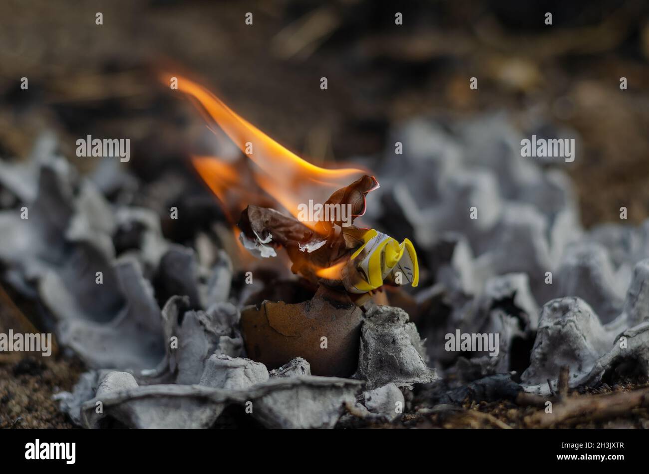 Ashes from a burnt egg tray and a burning chicken egg. An empty shell ...