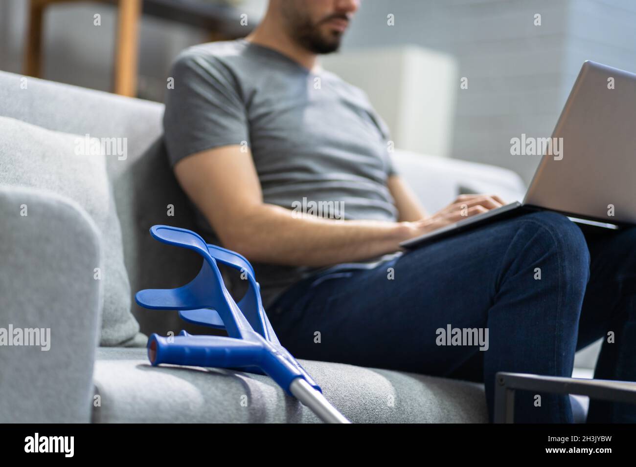 Injured Man With Broken Leg And Crutches Using Laptop Stock Photo - Alamy