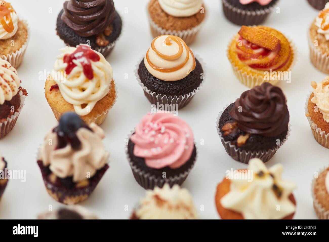 Assorted many different colorful cupcakes with decorations and toppings ...