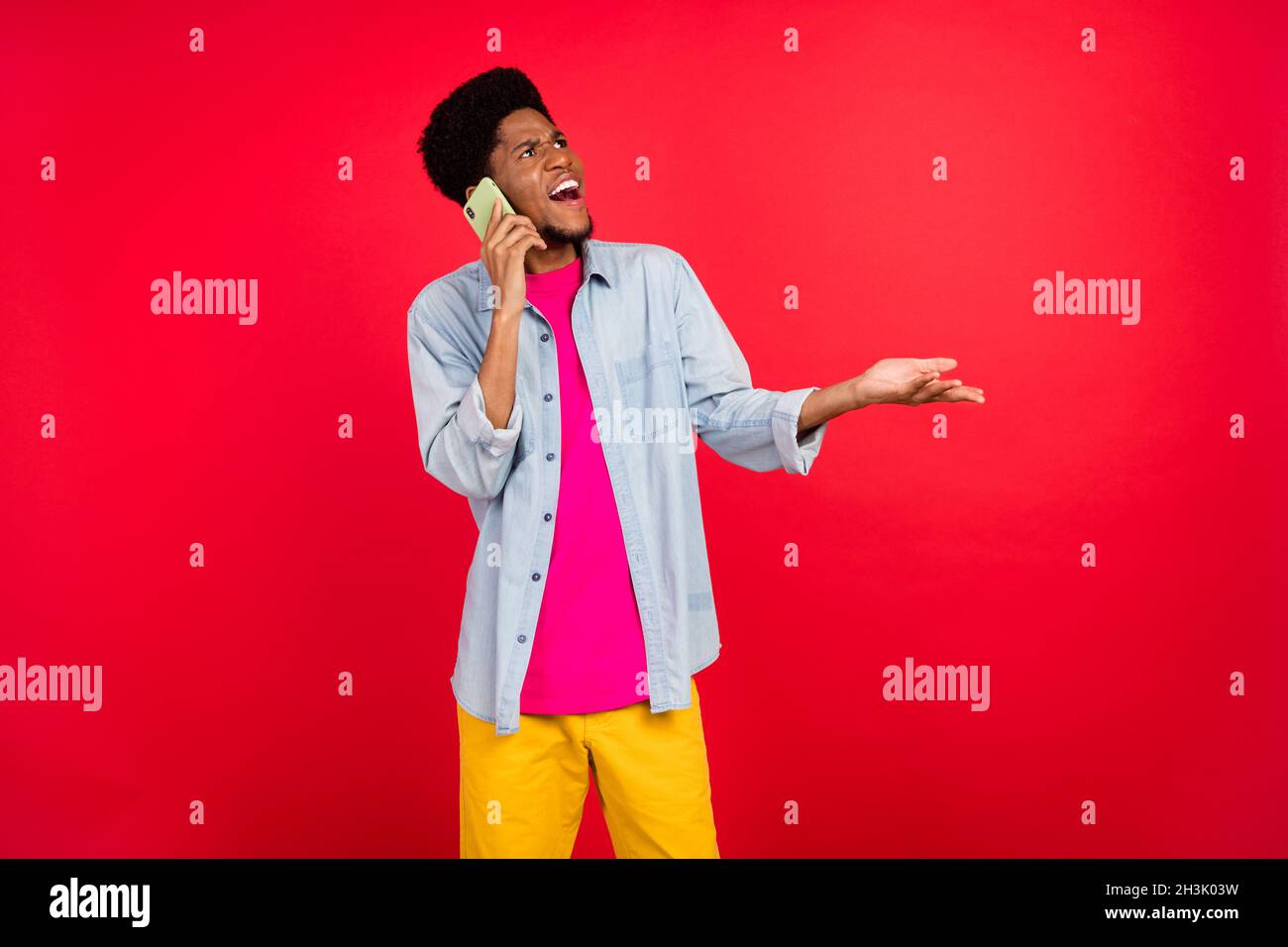 Photo of young afro guy angry mad speak talk smartphone amazed shocked ...