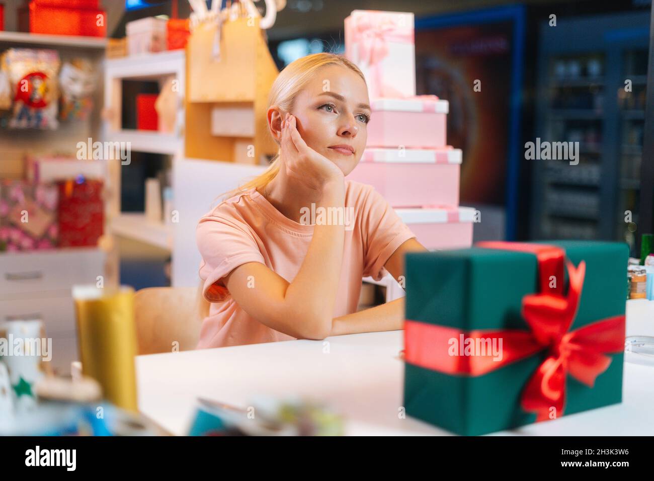 Close-up of sad attractive young sales woman sits at counter of holiday ...