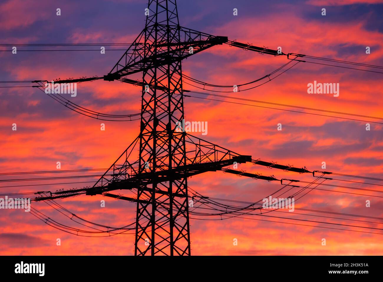 High voltage pylon towards sunset Fire red sky Stock Photo - Alamy