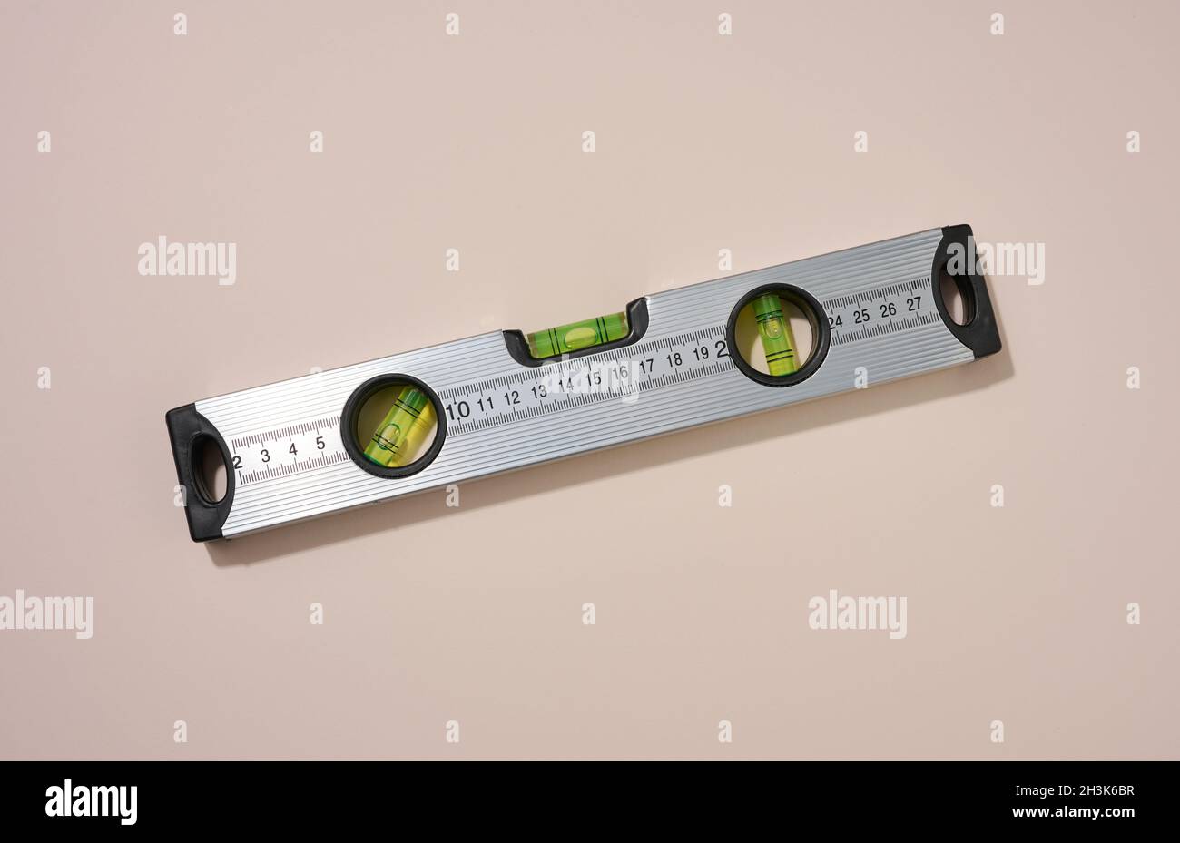 metallic building level on a beige background. Measuring instrument of ...