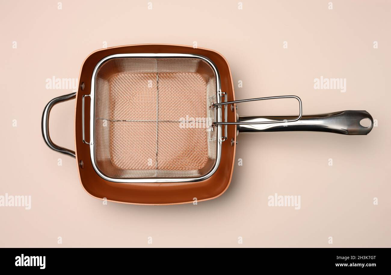 empty copper deep frying pan with grill grate on beige background. View ...