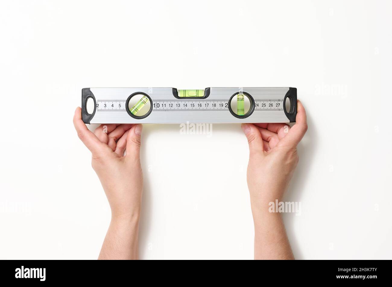 female hands holds a gray metallic building level on a white background ...