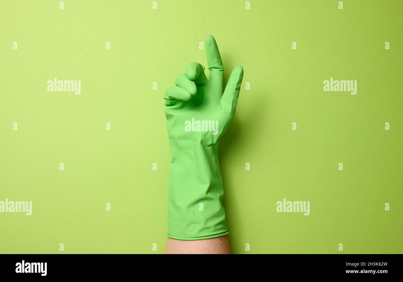 hand in a rubber green glove for cleaning on a green background, part ...