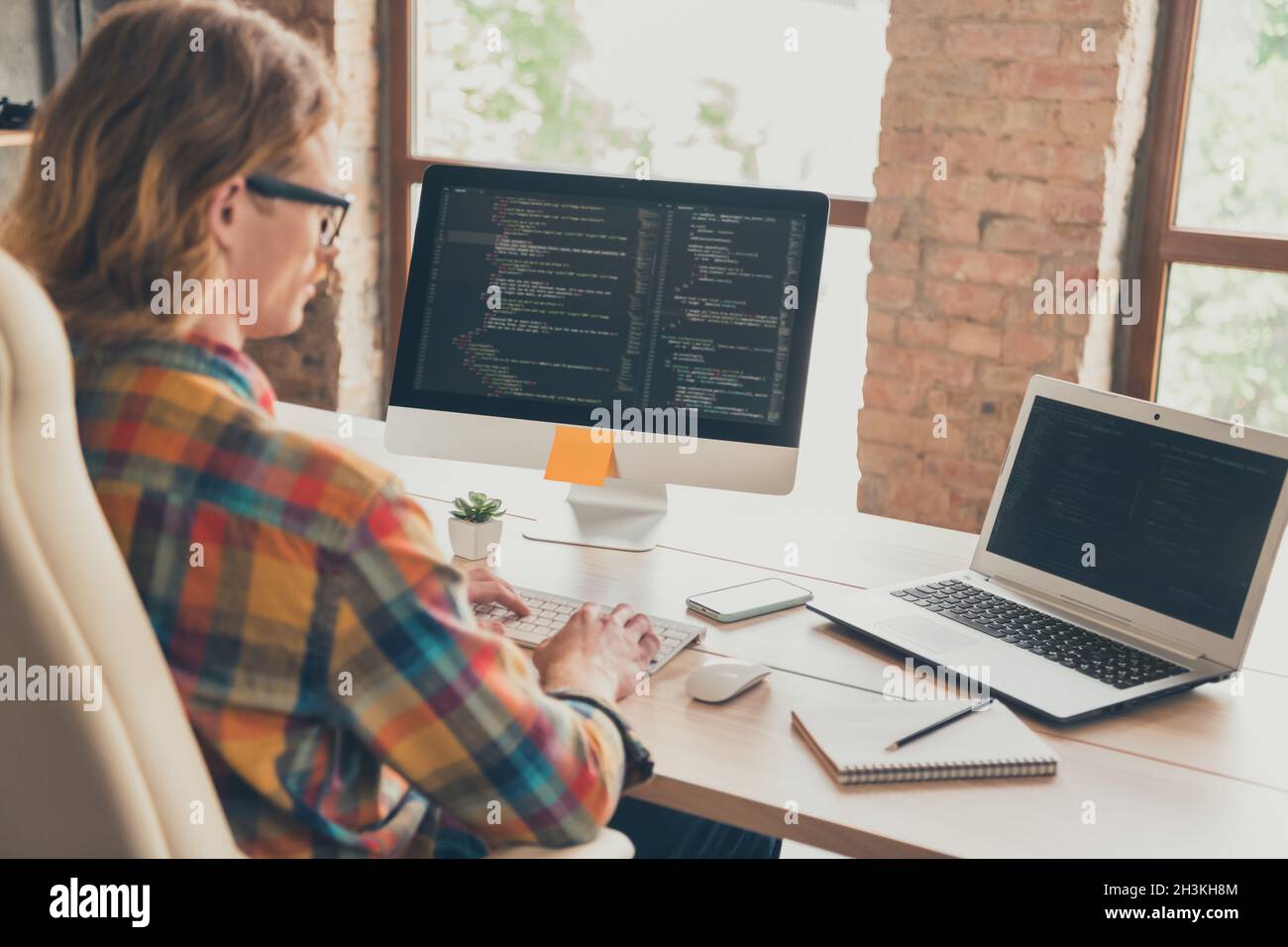 Back rear view photo of young man use laptop programmer coder jawascript linux developer sit ...