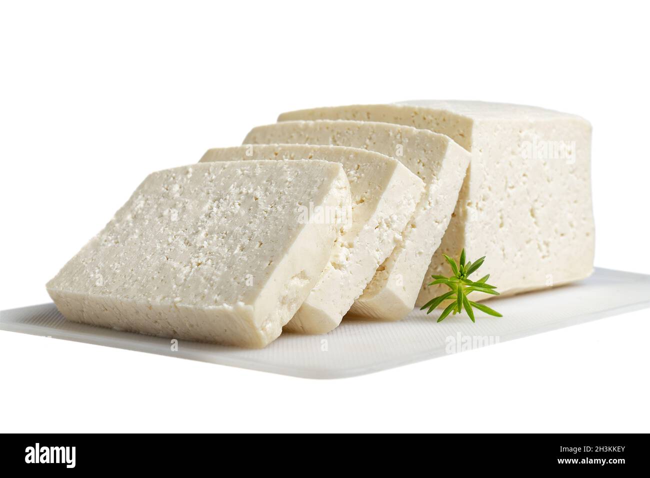 White cheese cut into several pieces on a white surface and white ...