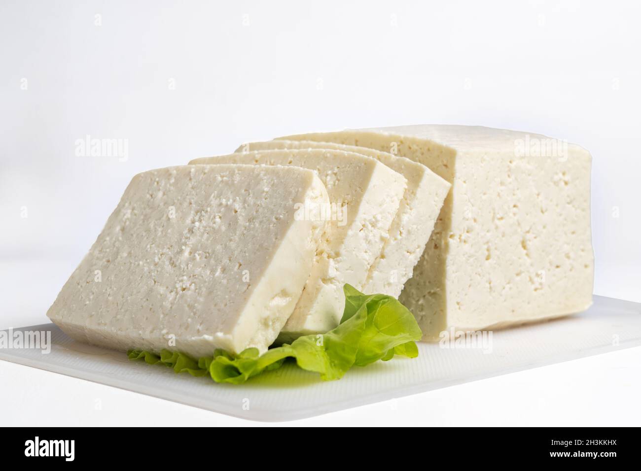 White cheese cut into several pieces on a white surfaceand white ...