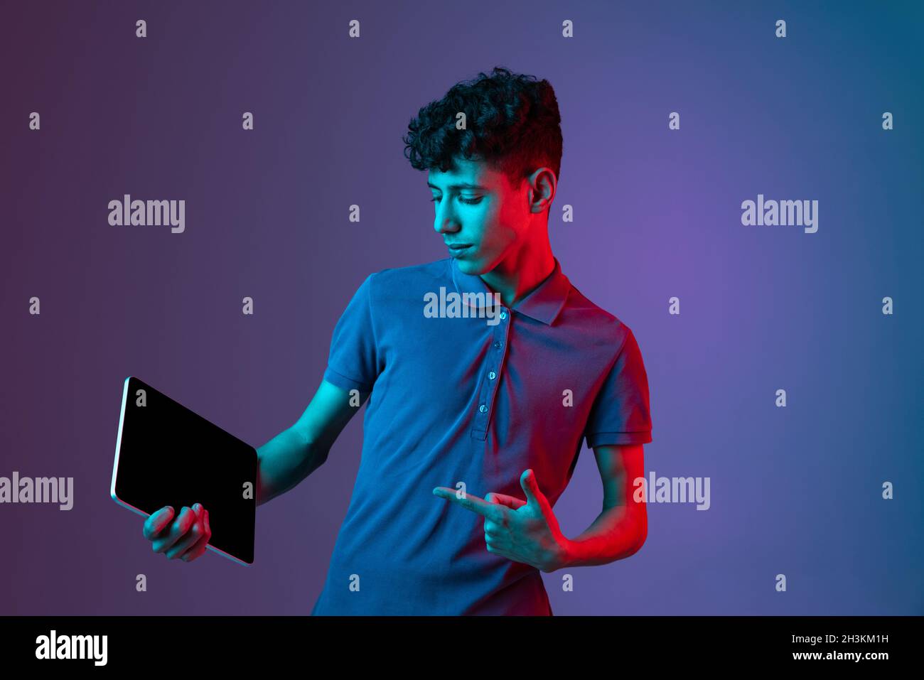 Cropped portrait of young boy pointing at tablet screen isolated over ...