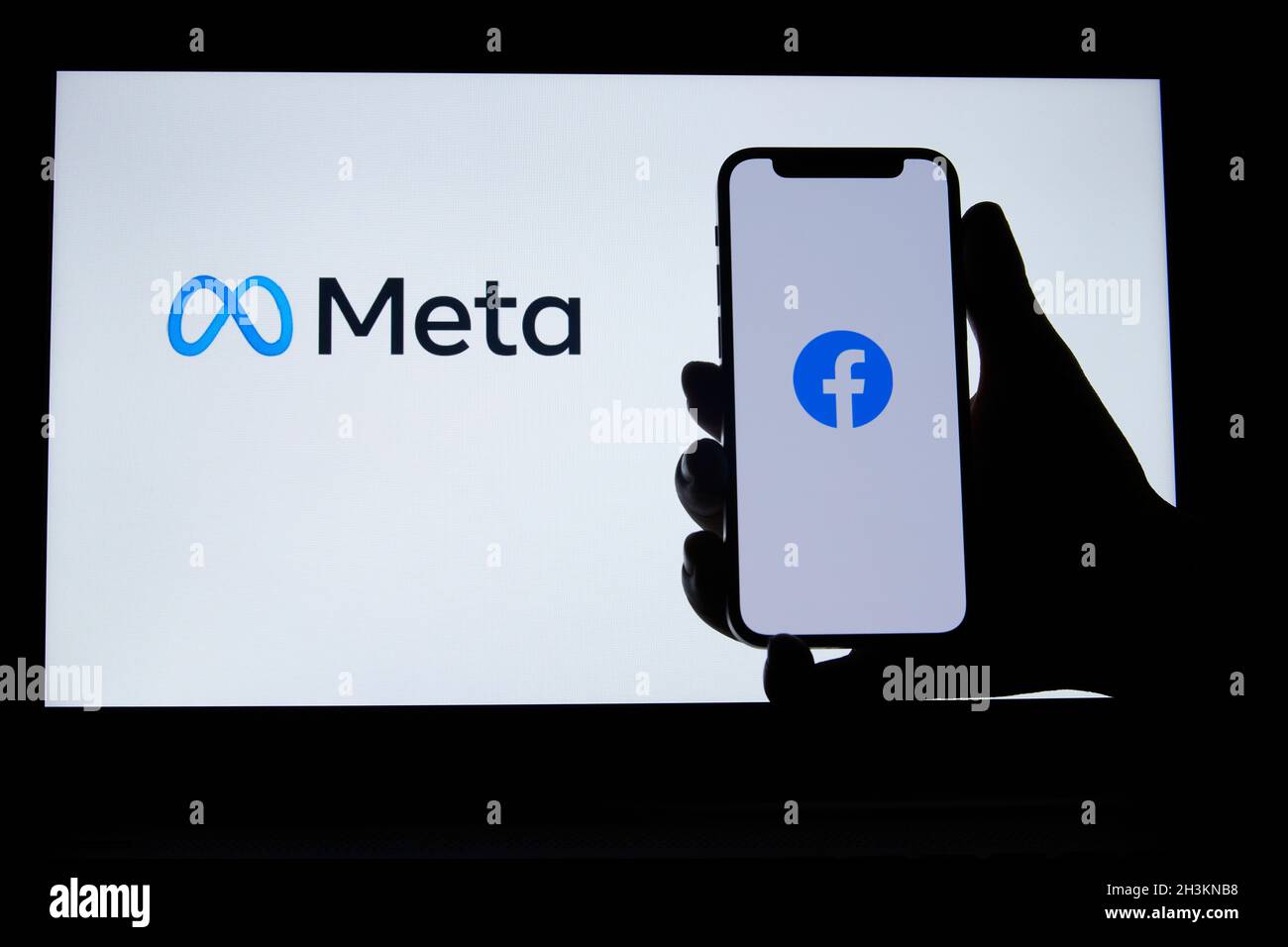 The logo of Facebook is seen on a smartphone and Meta's logo is ...