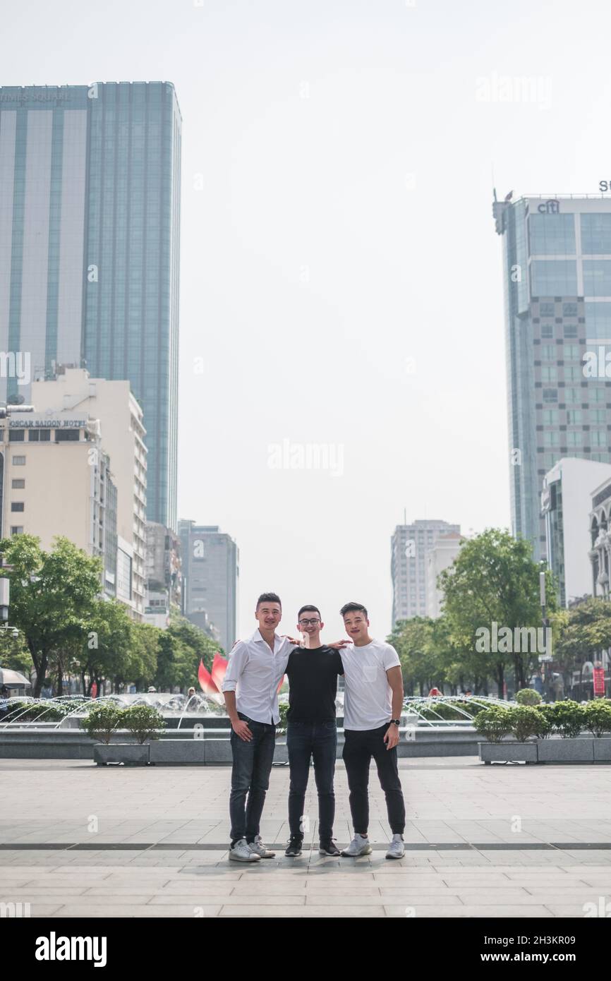 Three asian young men standing on the street and smiling. Asia, street ...