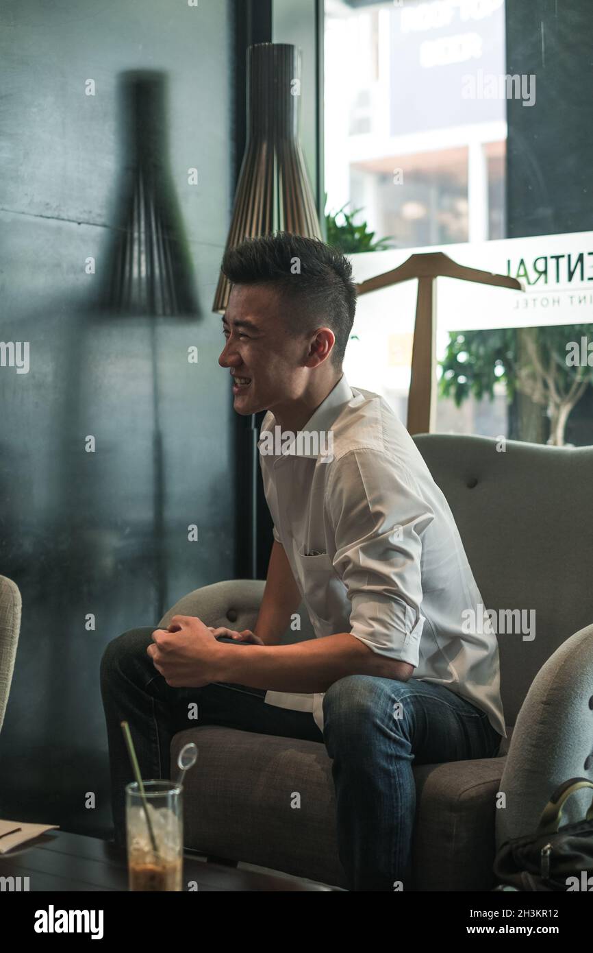 Asian young handsome man sitting in coffee shop, talking and smiling ...