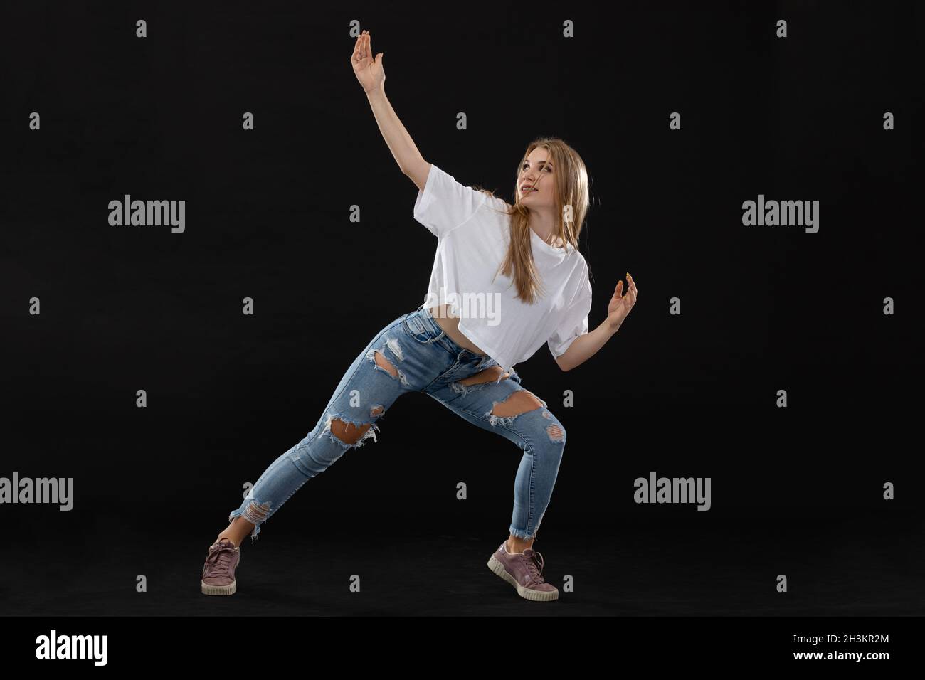 A teenage girl is performing a pose from a dance routine while standing ...