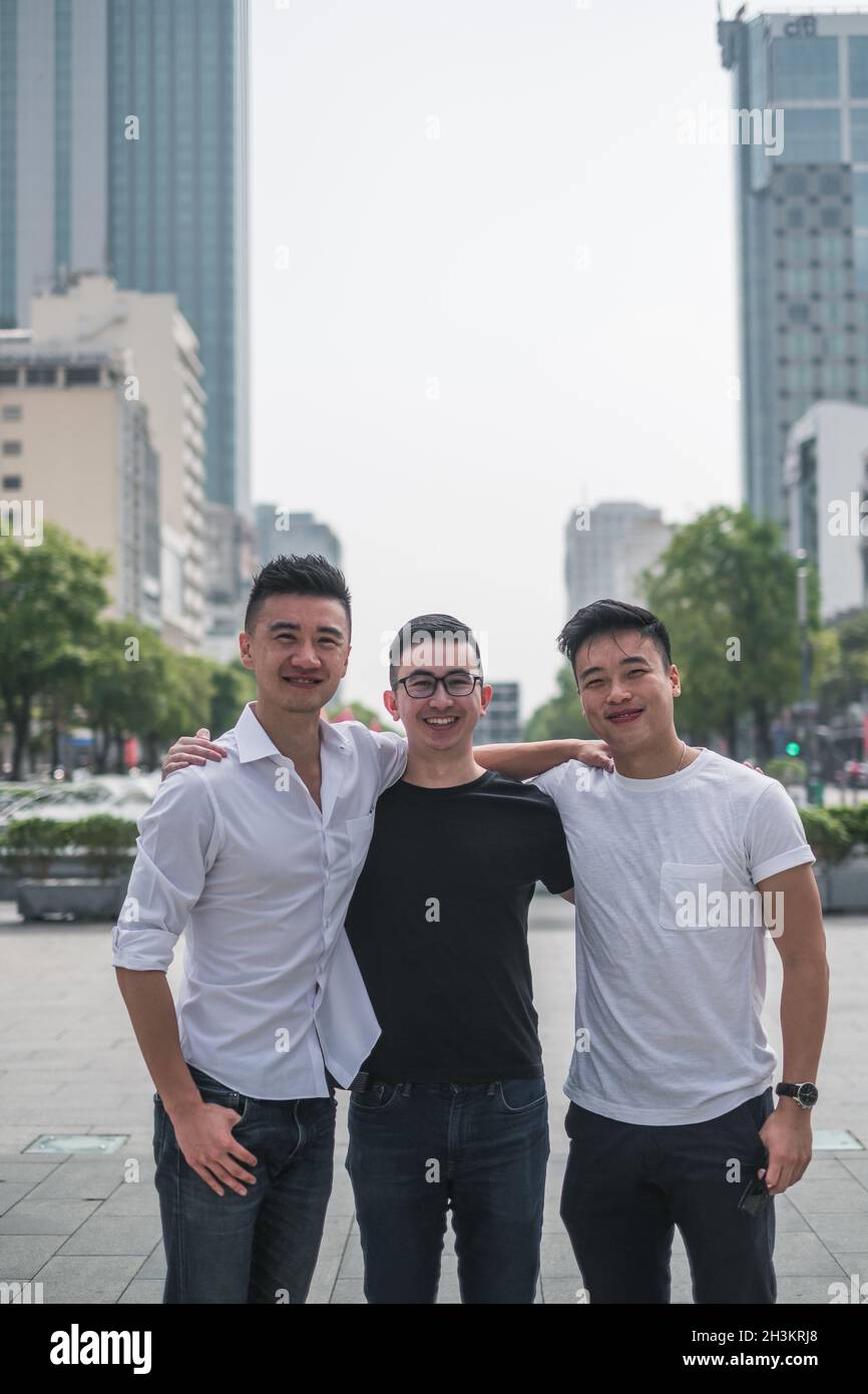 Three asian young men standing on the street and smiling. Asia, street ...