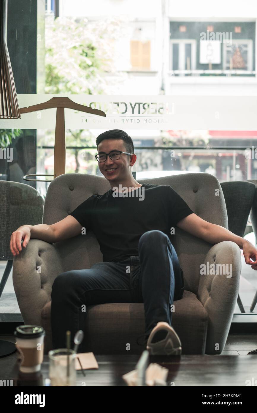 Asian young handsome man sitting in coffee shop, talking and smiling ...