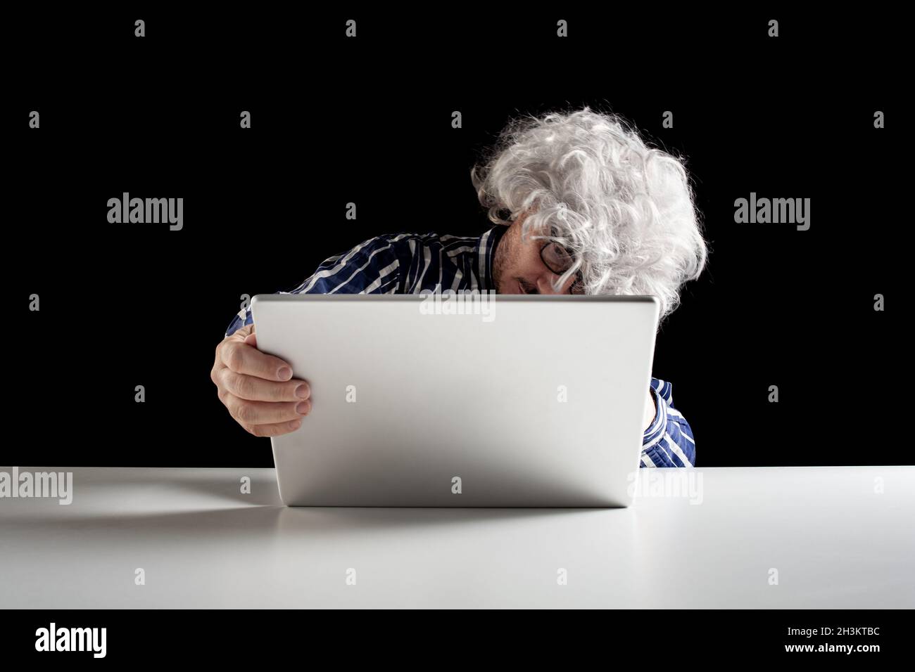 An elderly man does not know how to use the computer. He holds the ...
