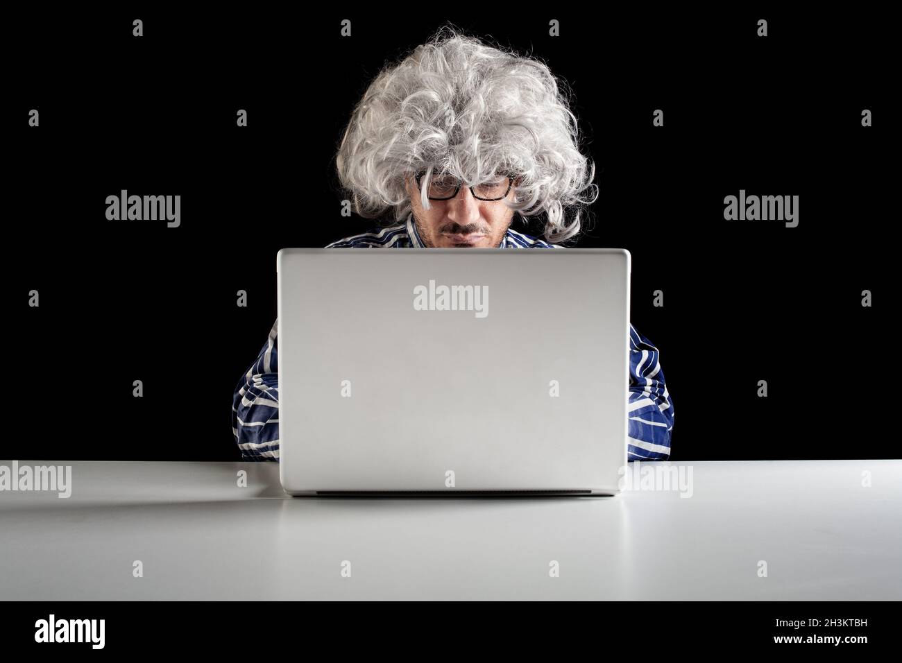 A boomer senior-focused concentrated sit at the desk looking at laptop ...