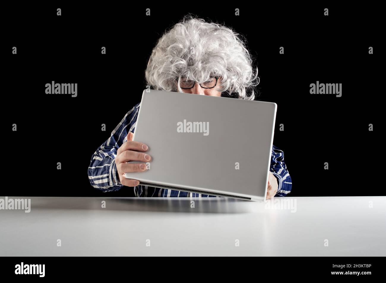 An elderly man does not know how to use the computer. He holds the ...
