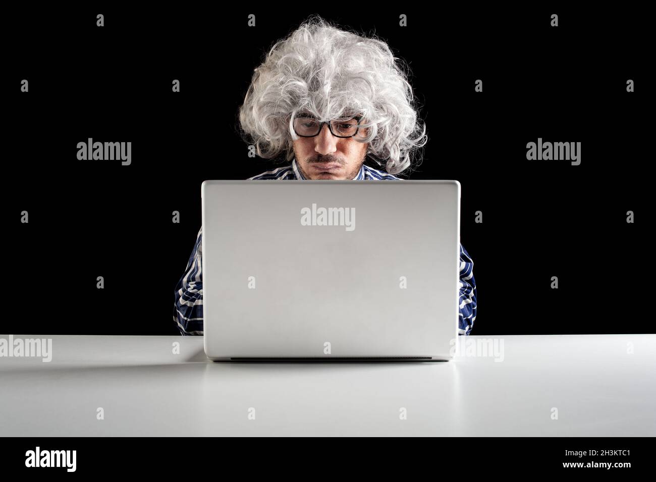 A boomer senior-focused concentrated sit at the desk looking at laptop ...