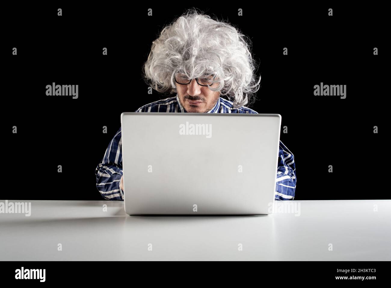 A boomer senior-focused concentrated sit at the desk looking at laptop ...