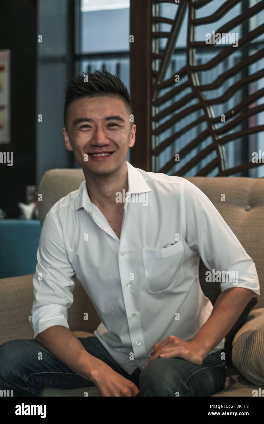 Asian young handsome man sitting in coffee shop, talking and smiling ...