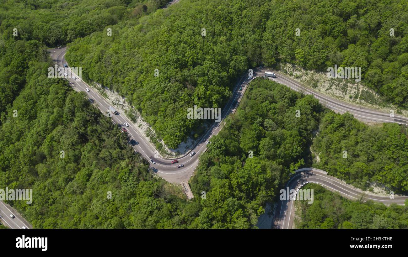 Curvy windy road between green mountain forest, top down aerial view ...