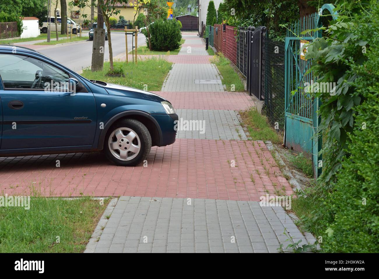 A passenger car standing on the sidewalk is blocking the pedestrian ...