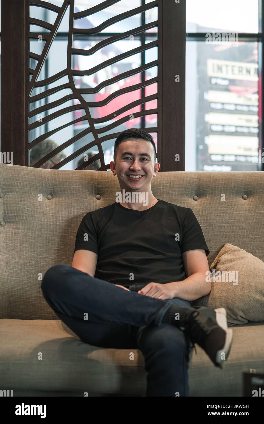 Asian young handsome man sitting in coffee shop, talking and smiling ...