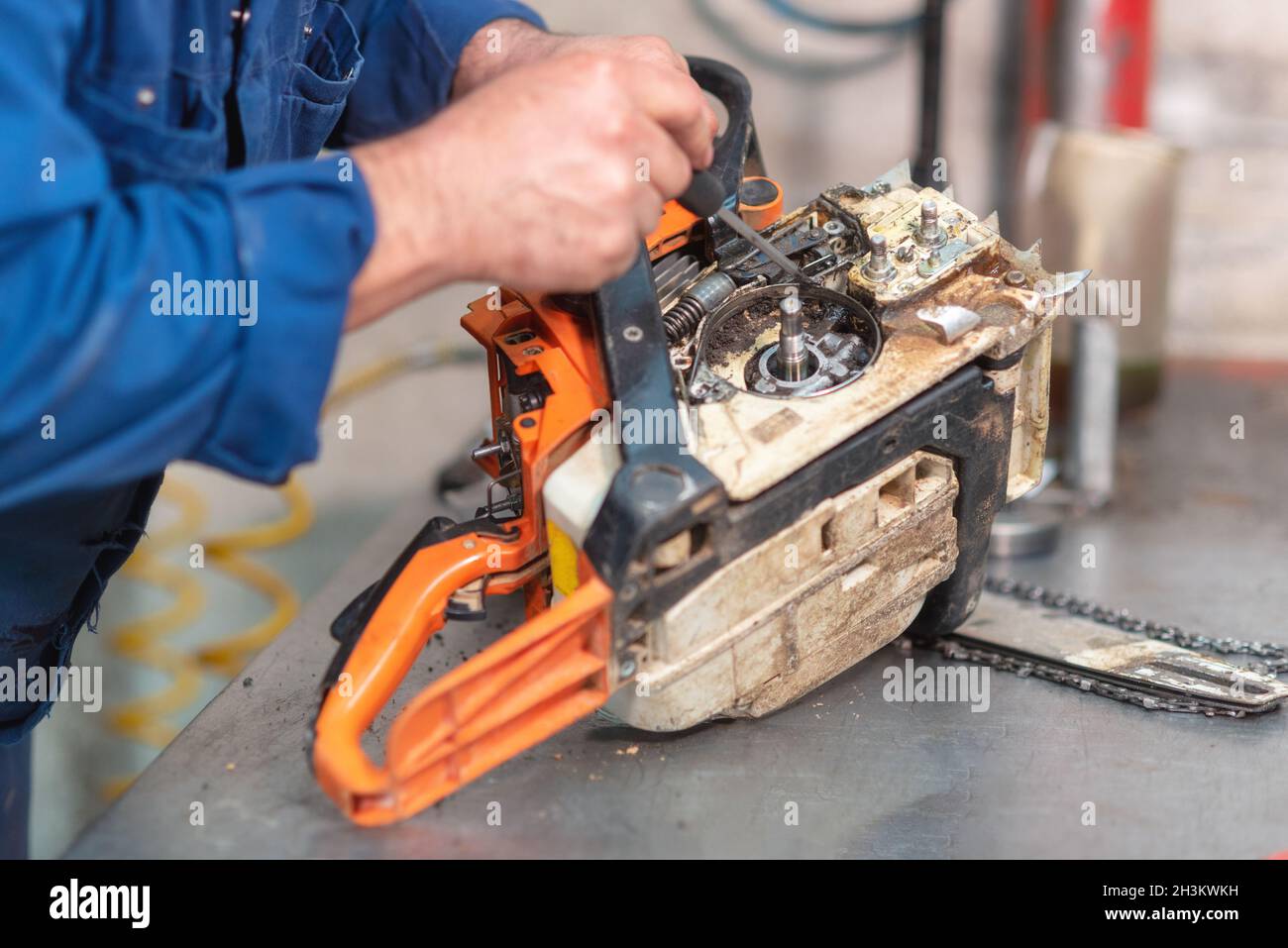Mechanic repairing a chainsaw. Man repairing a chainsaw in workbench ...