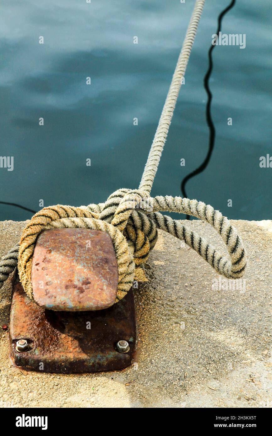 Rusty mooring bollard with tied rope in the port of Santa Pola ...