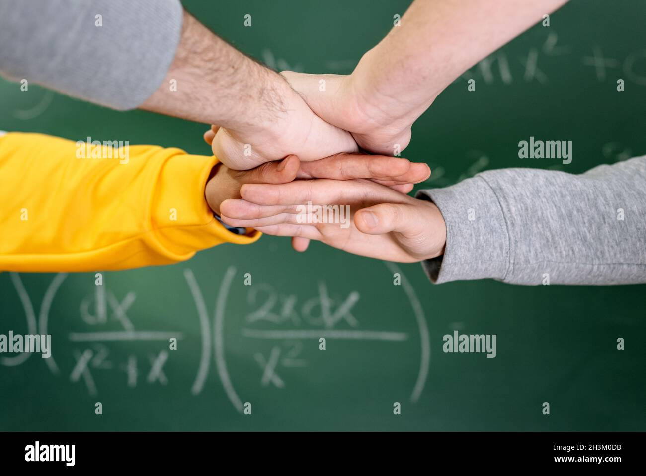 Students putting hands together at the college with a blackboard in the ...